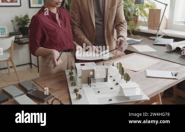 Tilt-up medium slowmo of couple of professional architects examining ...