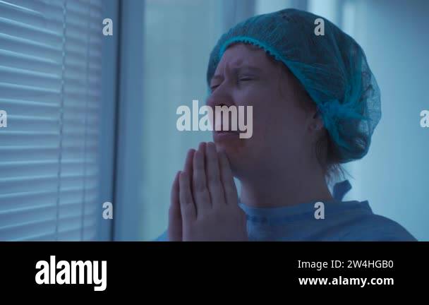 Stressed woman with facial injuries crying and praying in hospital ...
