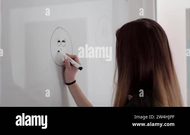 Young girl with long hair drawing a happy smiley face with a permanent ...