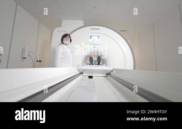 Doctor makes an MRI scan for a patient in a clinic. The girl lies in ...