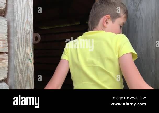 A teen boy opening a door of an abandoned wooden country house, he ...