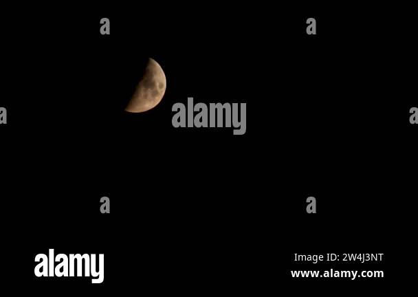 Half moon phase on black clear sky moving from top left to bottom right ...