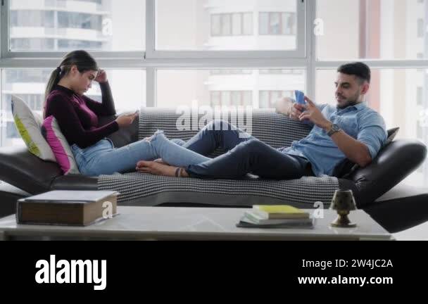 Young couple with smartphone at home. Man and woman ignoring each other ...