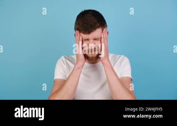 Sad unhappy young man calming down relieving headache emotional stress ...