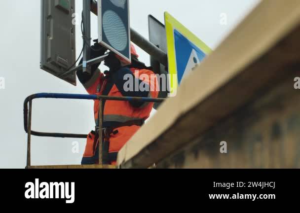 Worker in the elevator cradle fixes the LED traffic light. Road sign ...