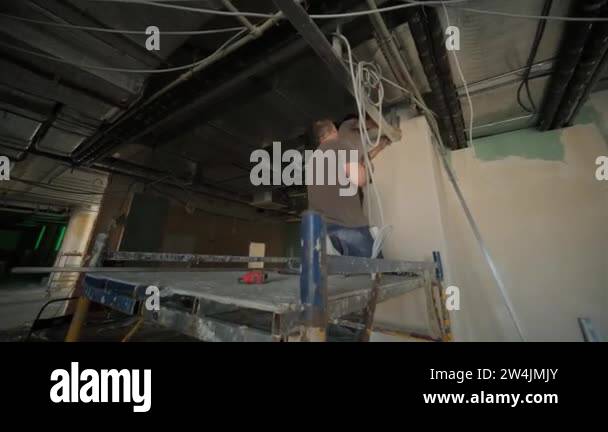 Construction worker assemble a suspended ceiling with drywall and ...