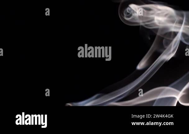 Smoke streaming in the dark from a burning incense stick. Whimsical ...