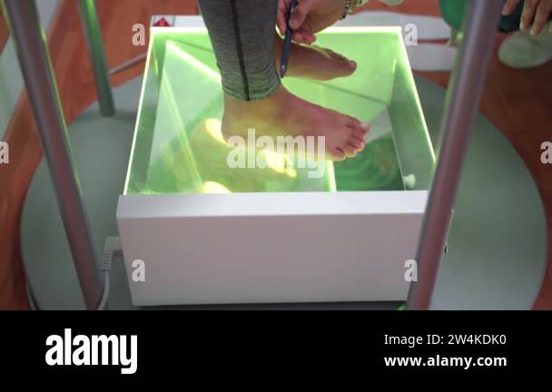 Barefoot patient staying on transparent glass surface with green neon ...