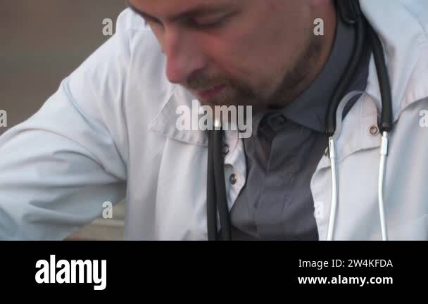 Tense doctor man examines x-ray on stairs outside clinic. Medical ...