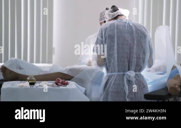 Rear view of a surgeon at work in operating room. Action. Side view of ...