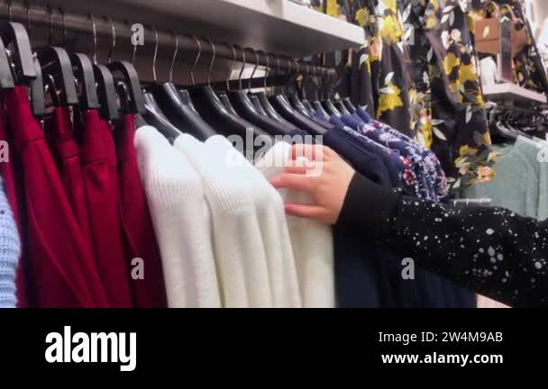 The hand of a young woman or teenager is sorting outfits, choosing from ...