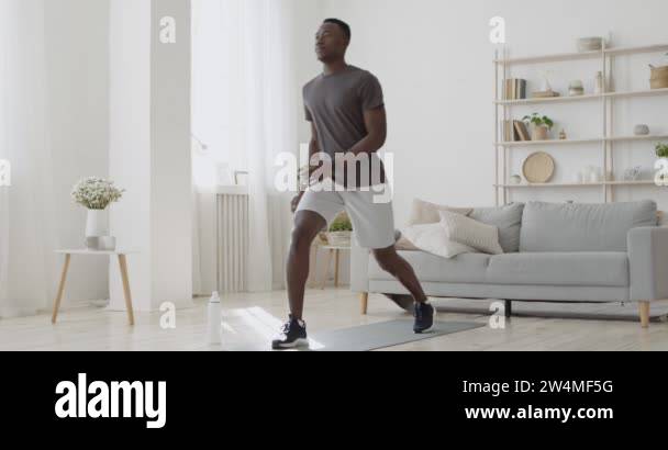 Athletic black man doing forward lunge exercises at home, training legs ...