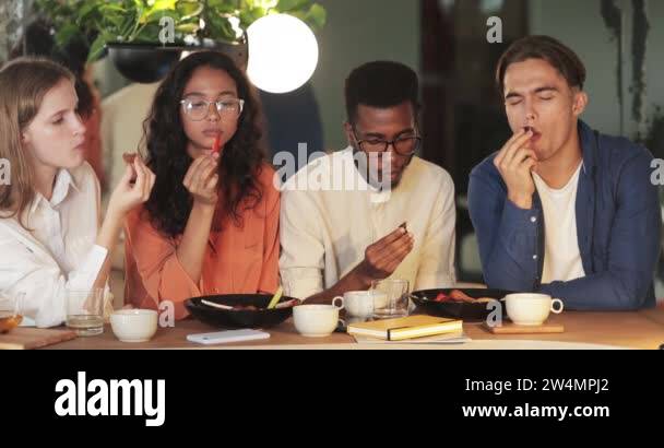 Crop view of happy friends enjoing tasty meal while sitting in modern ...