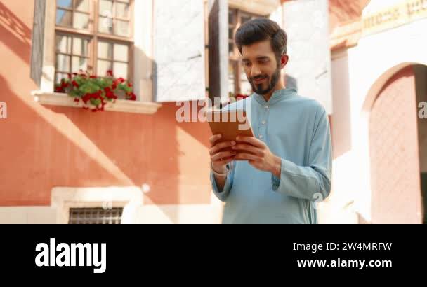 Hindu young handsome smiled man standing outdoors at street on sunny ...
