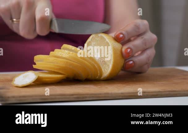 Hand holding knife for cutting lemon, cutting block full of sliced ...