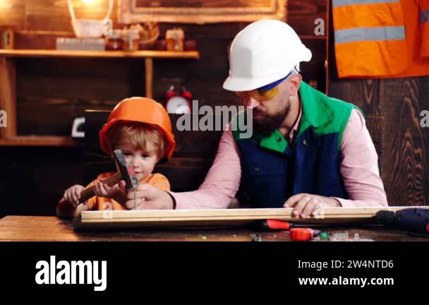 Father teaching little son to use carpenter tools and hammering. Parent ...