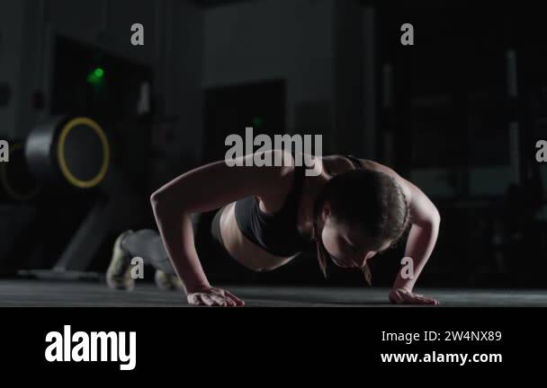 Athletic female fighter in gym, strong woman performs explosive push ...