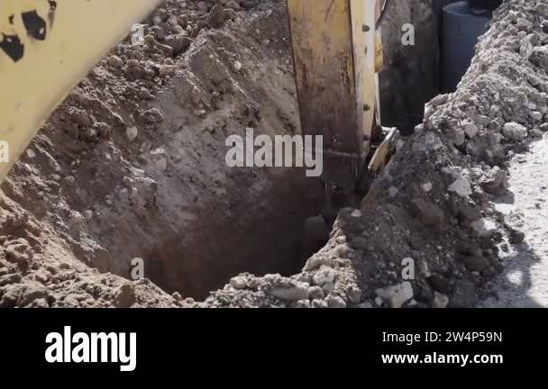 Big metal excavator bucket scoops up dirt while digging a ditch during ...