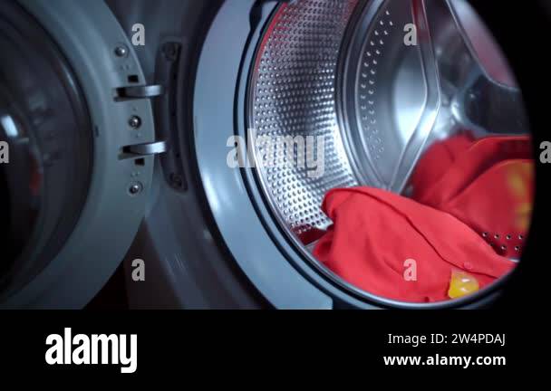 Woman hands throwing three yellow liquid detergent capsules for washing ...