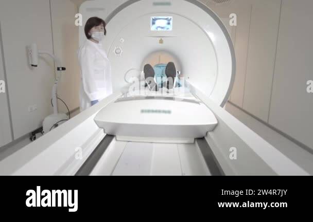 Doctor makes an MRI scan for a patient in a clinic. The girl lies in ...