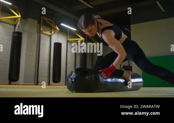 Female fighter trains his punches, beats a punching bag while lying on ...