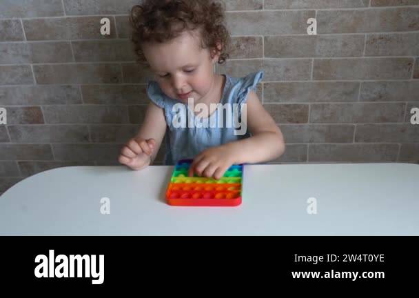 Child Playing Poppit Fidget Toy. Young Little Girl At Home Holding Pop ...