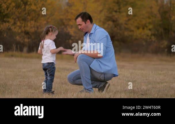 Dad plays with his little daughter teaches to shake hands, hello daddy. Father and beloved child ...