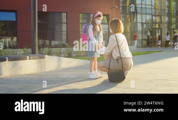 Caucasian mother talking to daughter pupil in mask outdoors before ...