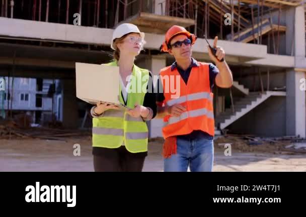 Young engineer lady with a laptop walking beside the foreman middle ...