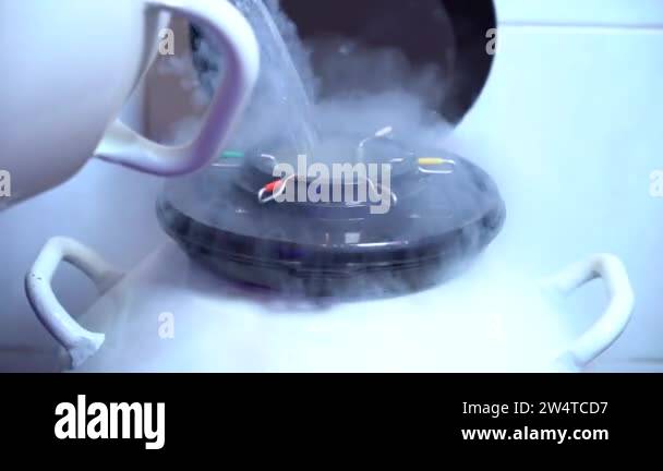Scientist opens a Cryogenic container with medical samples and pour ...