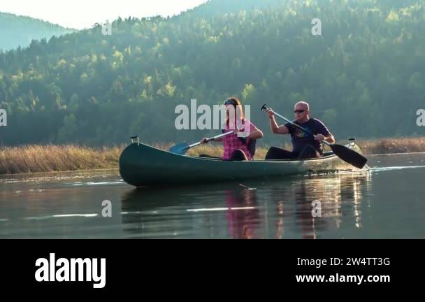 A beautiful scene of two people riding a canoe. The woman is paddling ...
