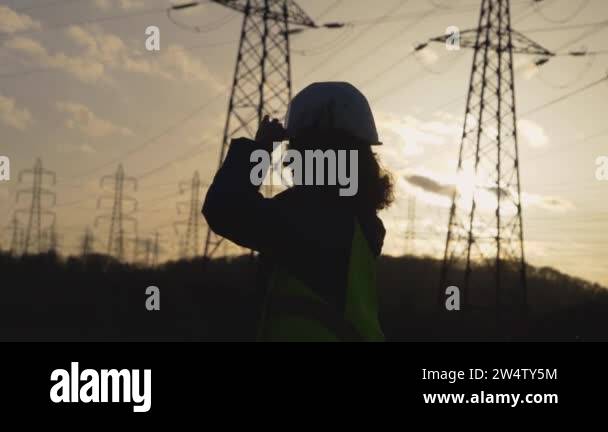 Young Woman Constructor Jump in screen in Slow motion footage.on field with electricity towers ...
