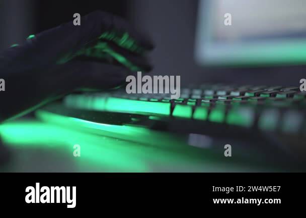 Close-up of hand in black glove typing on computer keyboard at night in ...
