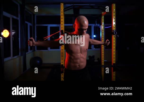 Front view of muscular shirtless male bodybuilder training chest in gym ...