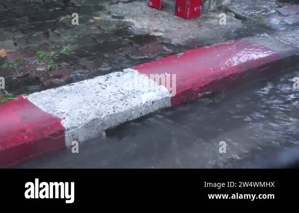 Water draining down roadside gutter flooding during rain strom season ...