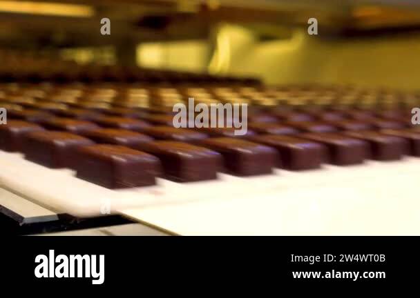 Chocolate confectionery products are moved along the conveyor of the confectionery shop to the ...