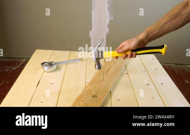 Hammer a nail into the Board.A construction worker throws and catches a ...