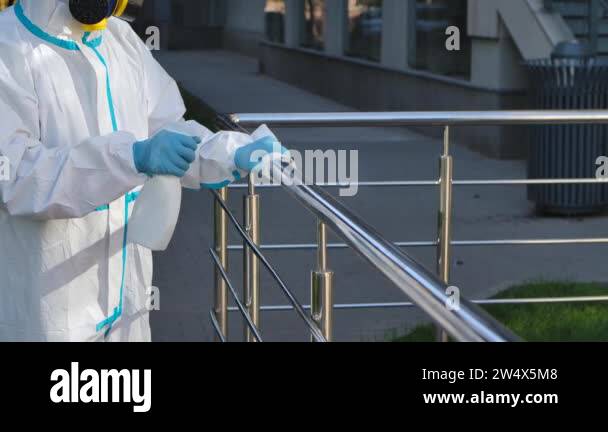 Side view of a young sanitary worker wearing a protective suit and a ...