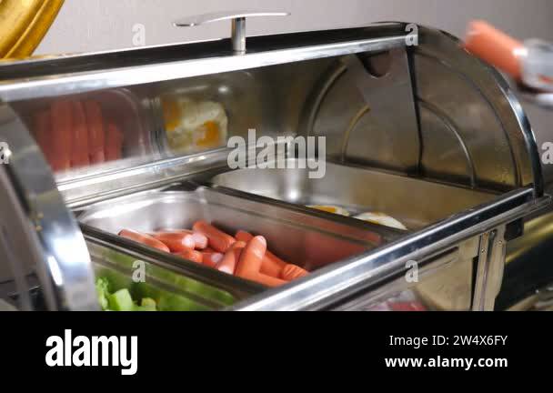 Buffet heated trays with sausages, boiled broccoli and fried eggs in ...