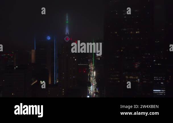 Drone flying along street between tall commercial buildings around ...