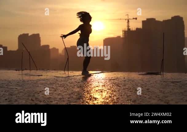 Flexible female gymnast jumping acrobatic split tricks with reflection ...