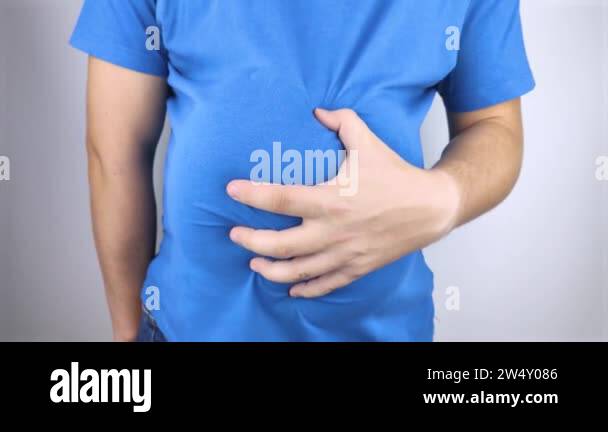 The man is holding onto his swollen belly. Bloating, flatulence, gas ...