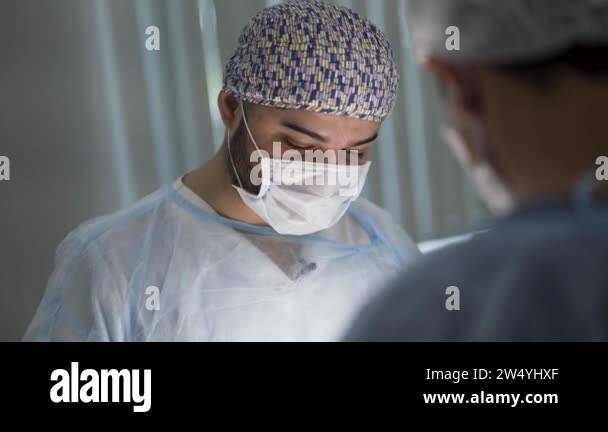 Close up of two male surgeons looking down at work. Action. Men doctors ...