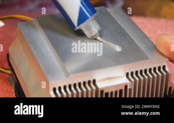 Application and distribution of thermal paste from a tube to a PC cooling radiator. Close-up of ...