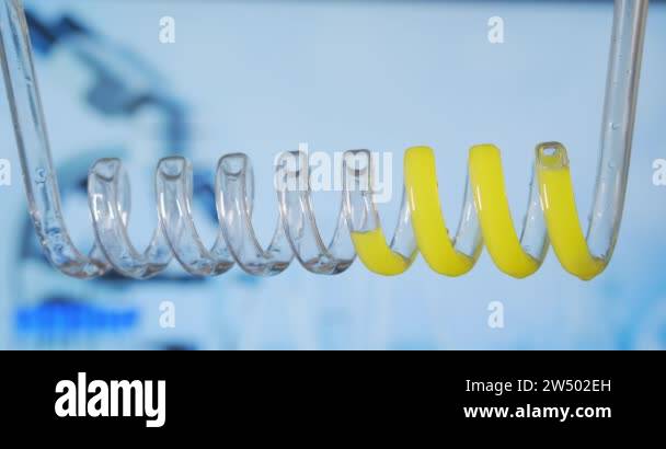 Close up and slow motion of yellow liquid spiraling horizontally from ...