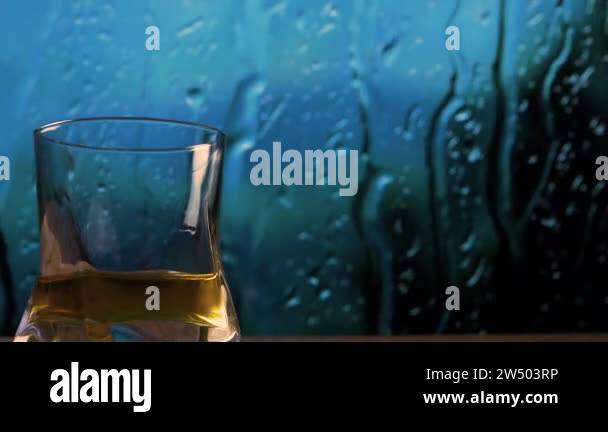 A glass of whiskey on the background of the rain window, an alcoholic ...