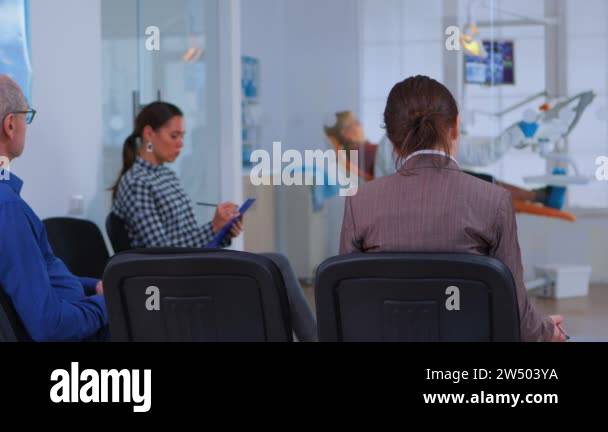Back view of patient filling in dental form sitting on chiar Stock ...