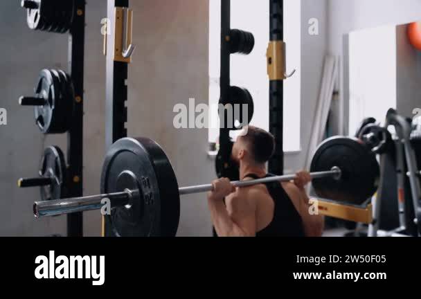 The landscape behind the bodybuilder performs barbell squats with ...