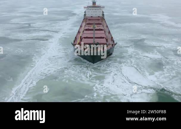 Aerial above epic huge steel ship breaks ice by bow of ship and floats ...