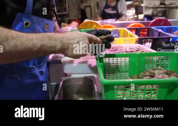 Oyster farmer opening oyster shells in a fish market Sete France ...